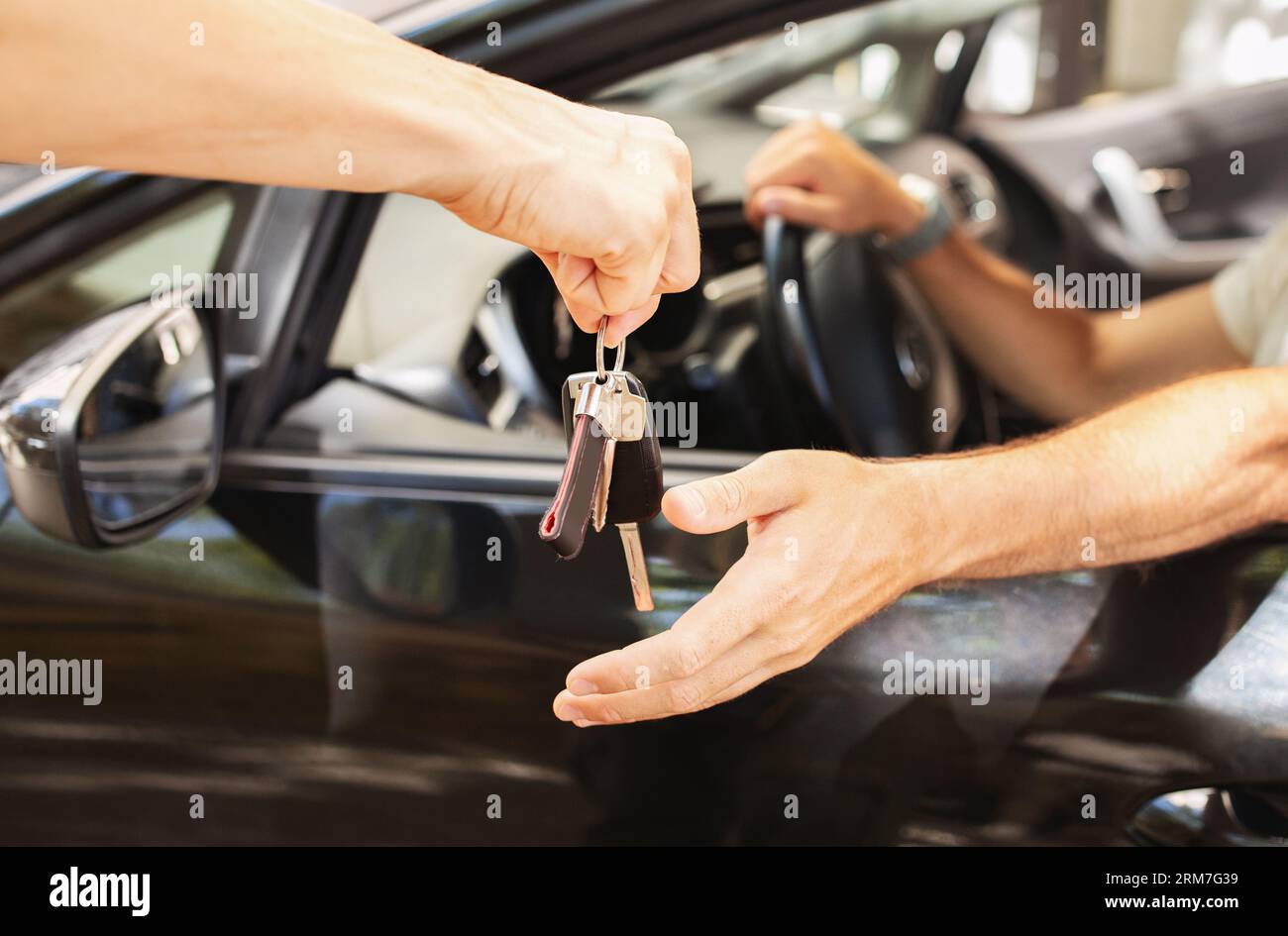 Valet parking worker giving key to man sitting in car Stock Photo - Alamy