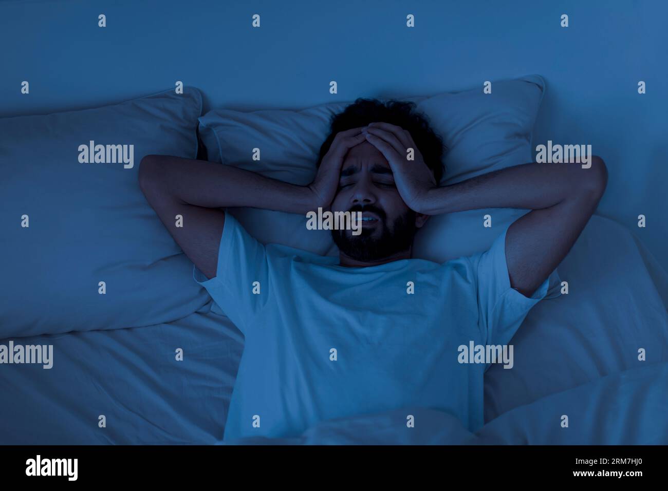 Sleeping Problem. Stressed young indian man lying in bed and touching ...