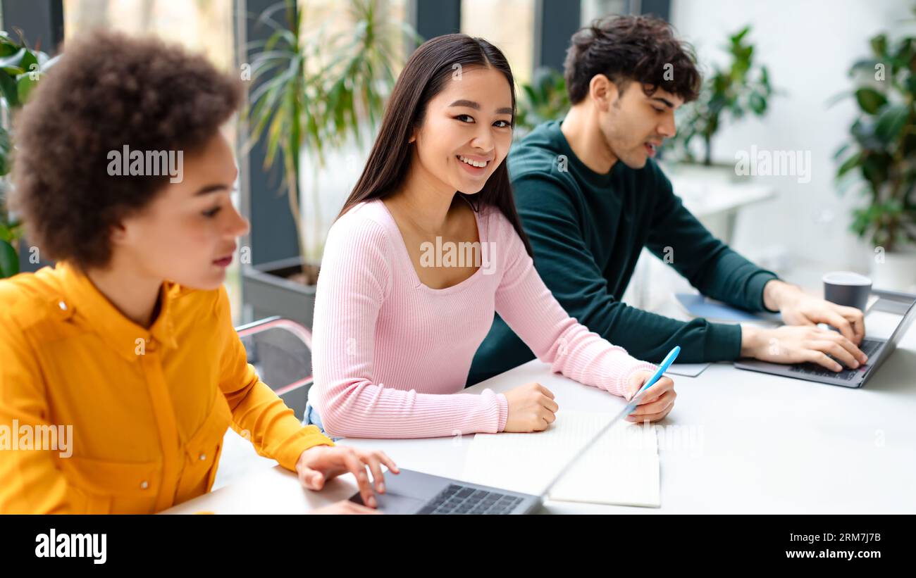 Study process. Diverse classmates sitting at desk, asian lady smiling ...