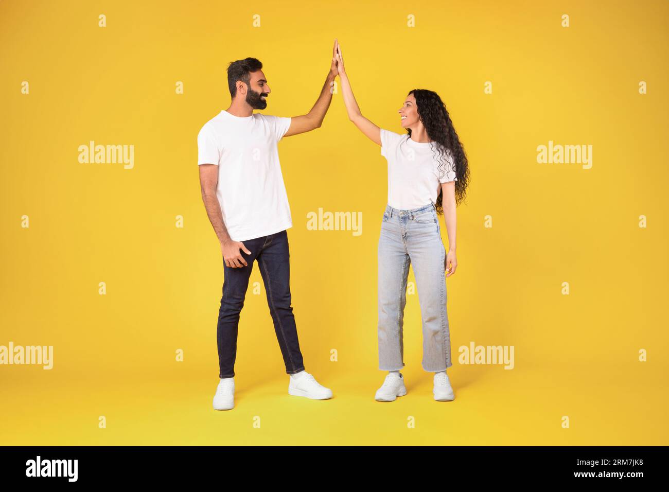 Arabic Couple Giving High Five Standing Over Yellow Studio Background ...