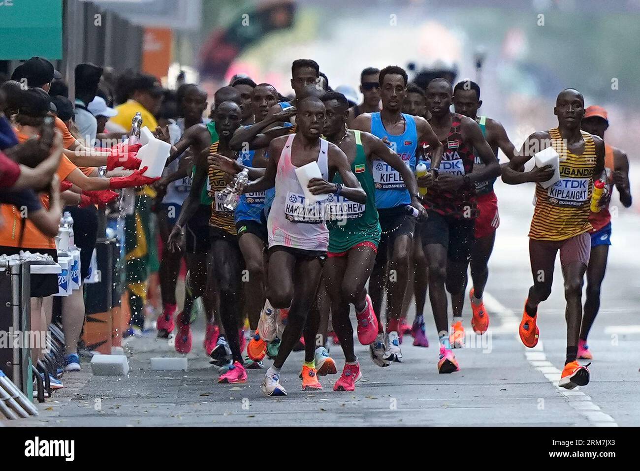 Victor Kiplangat of Uganda, right, runs with a wet sponge to cool off during the men's marathon ...