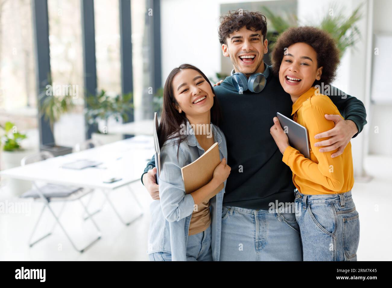 Three excited international students friends embracing and smiling at ...