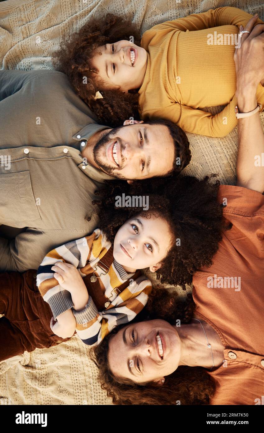 Face, family and top view of children and parents lying down together ...
