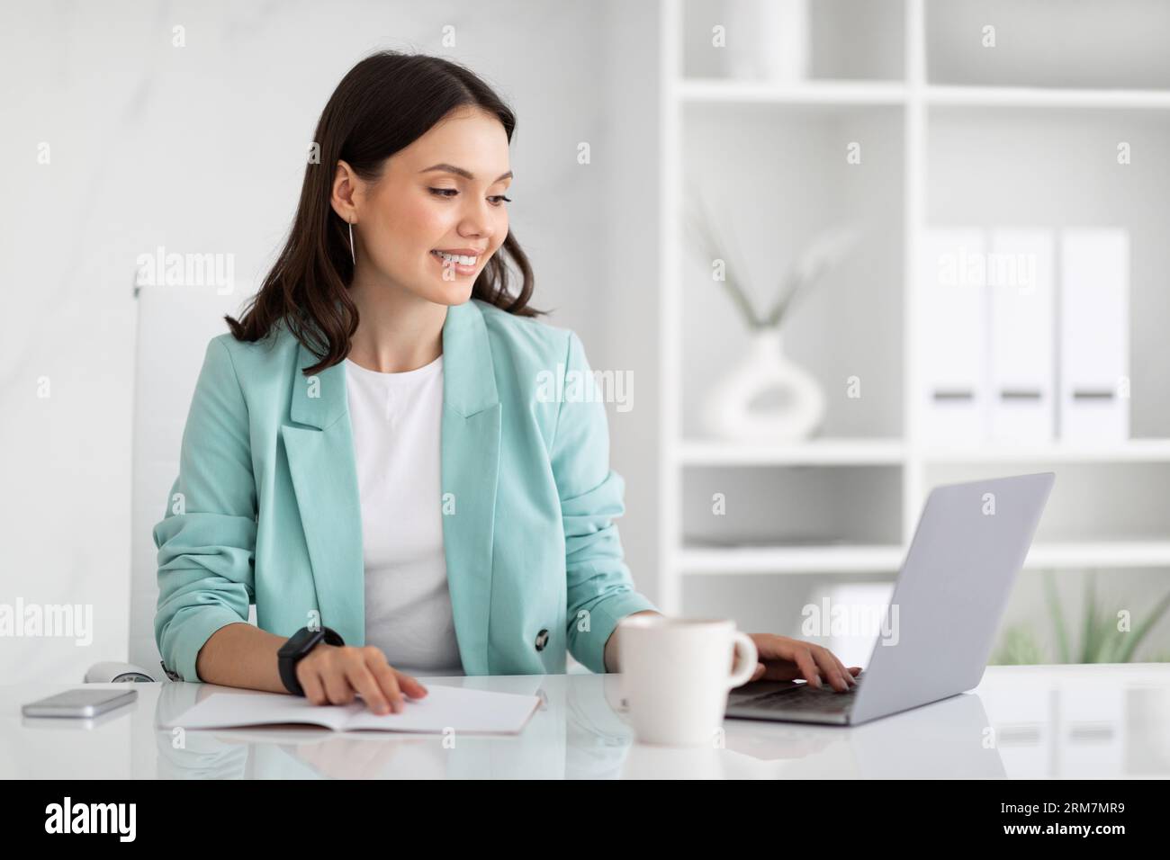 Glad millennial european business lady use computer to chat, work in white modern office ...