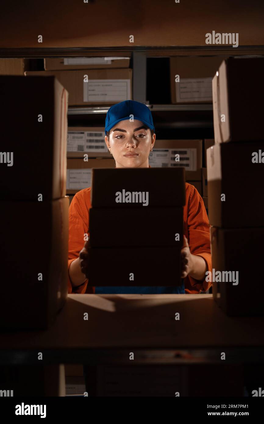 Warehouse female worker puts cardboard boxes on a shelf. Cardboard ...