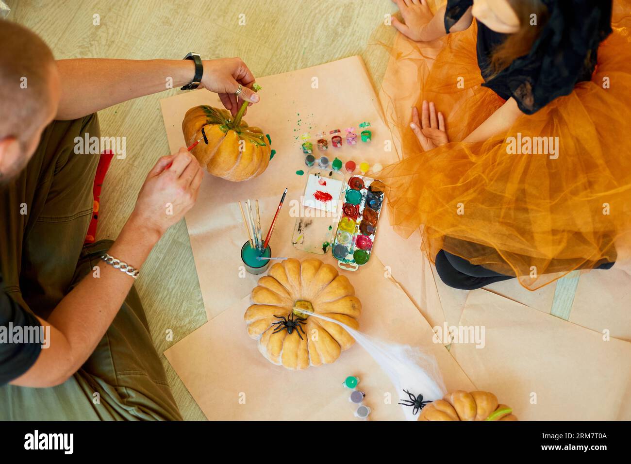 Man teaching a young girl how to decorate an orange pumpkin with a ...