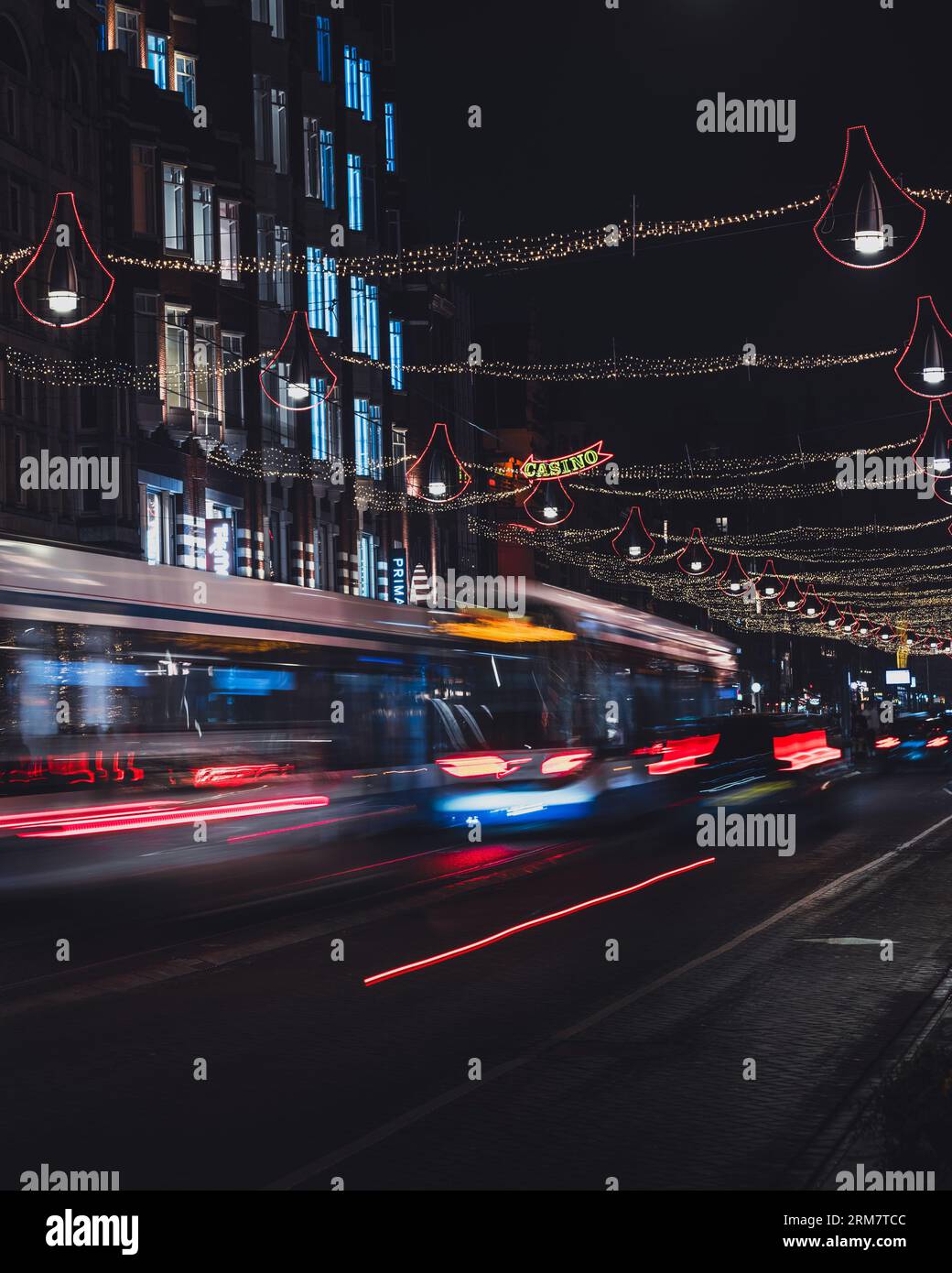 A vertical of tram driving on the street of Damrak in Amsterdam ...
