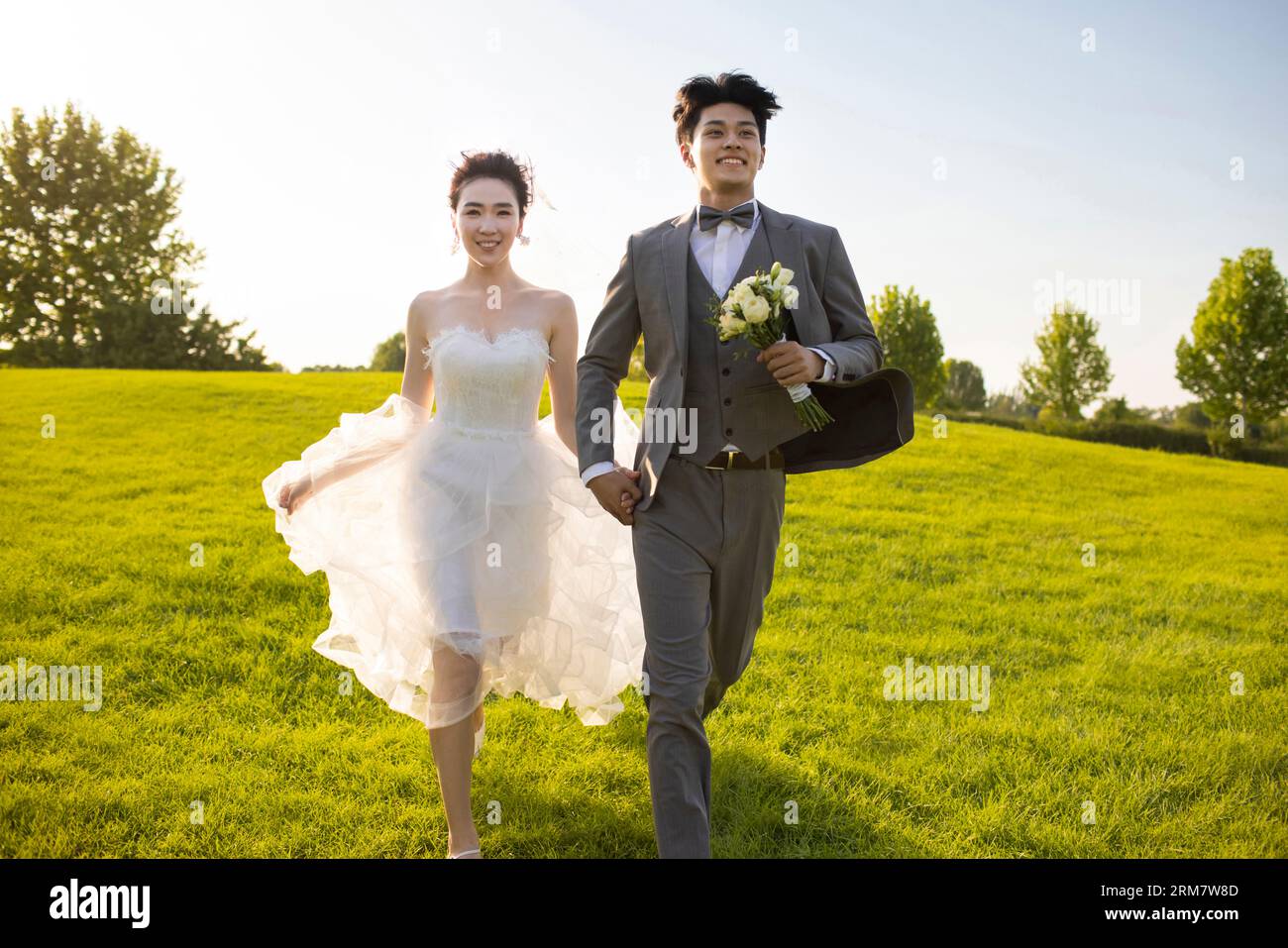 Happy bride and groom running on the grass Stock Photo - Alamy