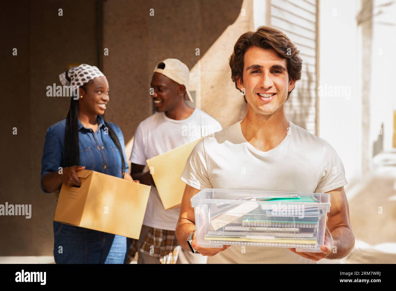 Happy young guy holding box with notepads outdoor Stock Photo - Alamy
