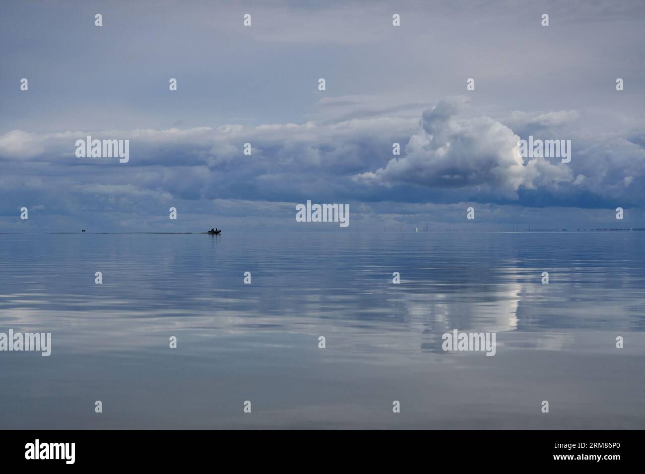 The surface of the sea like a mirror reflects the sky with clouds ...