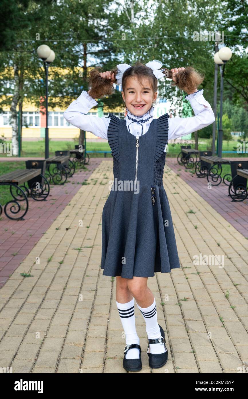 Cheerful funny girl with a toothless smile in a school uniform with ...