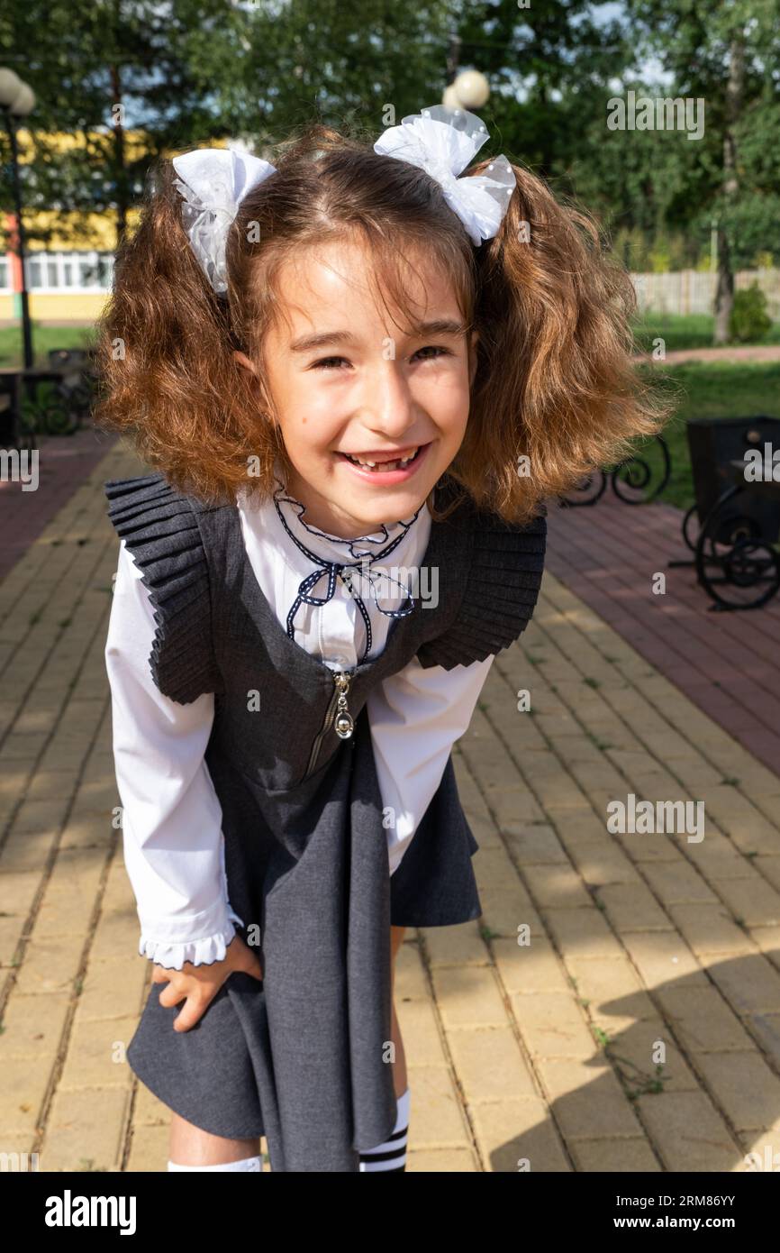 Cheerful funny girl with a toothless smile in a school uniform with ...