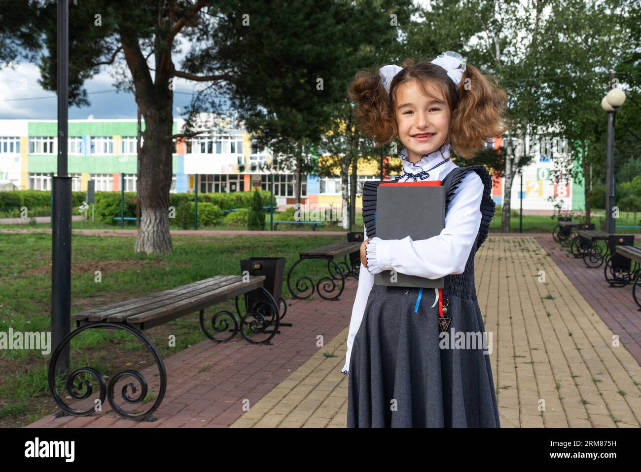 Girl with backpack, school uniform with white bows and stack of books ...