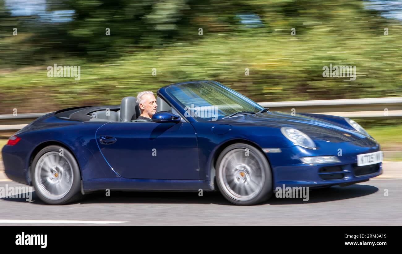 Milton Keynes,UK - Aug 23rd 2023. Man driving a blue open top Porsche ...