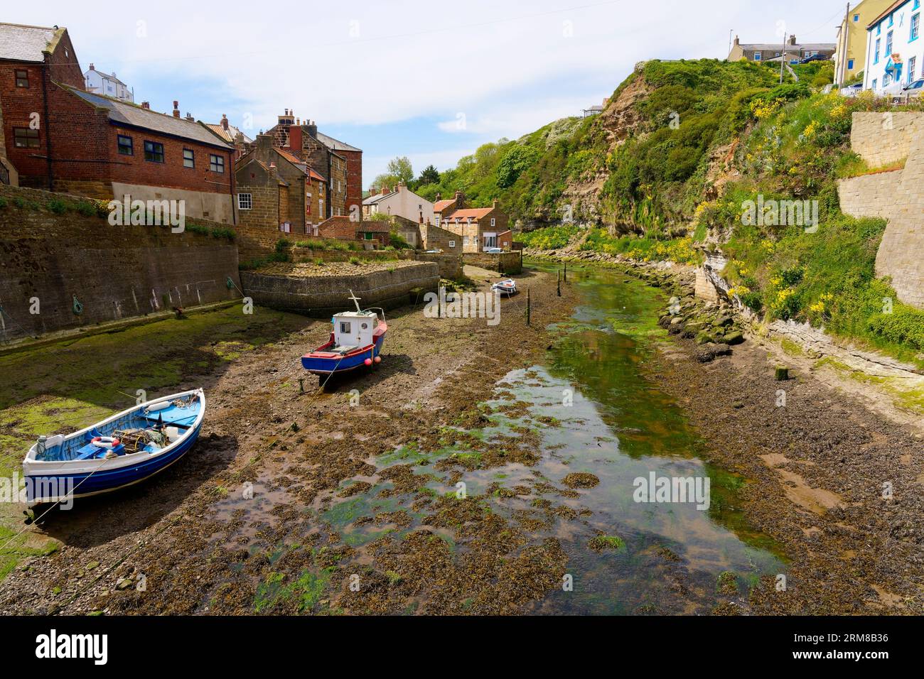 Small fishing boats rest on the bed of Staithes Beck in the coastal ...