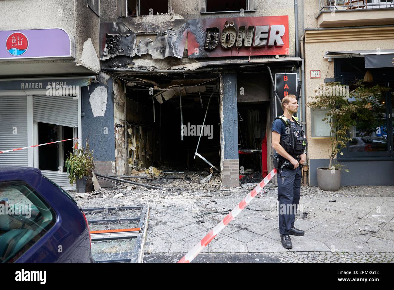 Berlin, Germany. 27th Aug, 2023. A policeman stands in front of a burnt ...