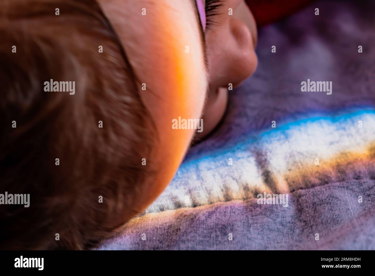 Baby resting in bed with rainbow on head Stock Photo - Alamy