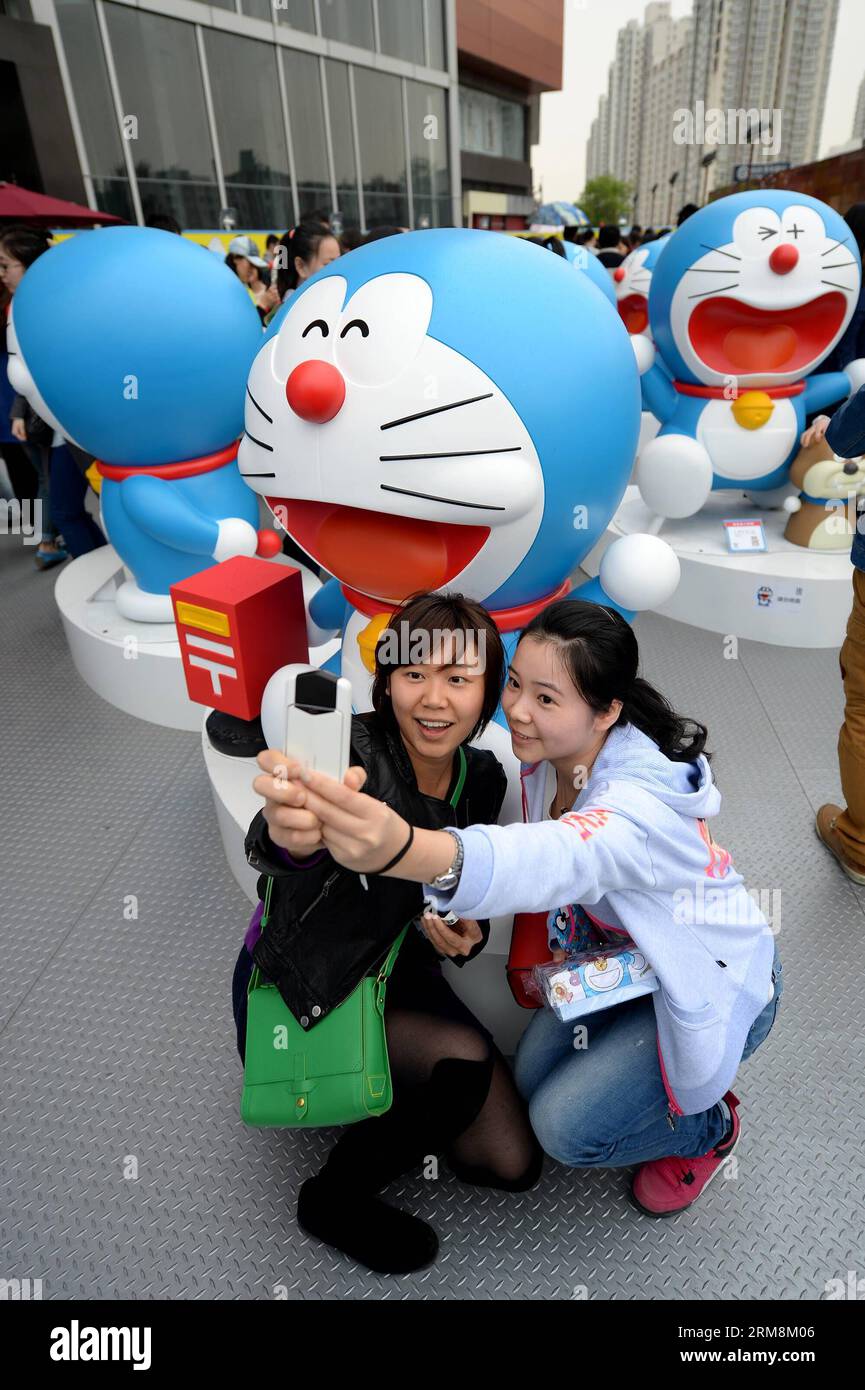 Visitors take a selfie in front of a Doraemon figure at an exhibition ...