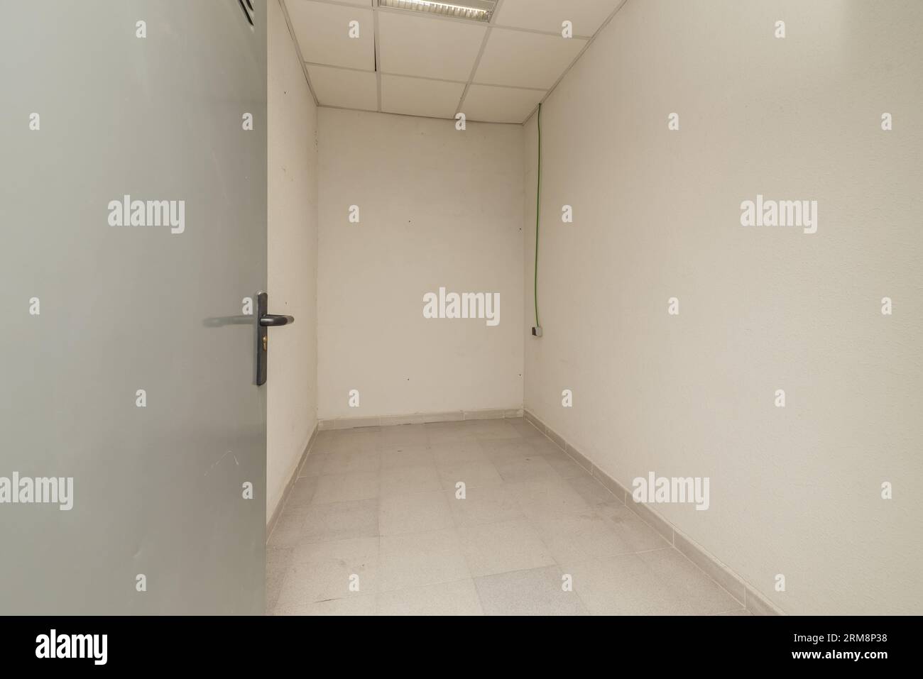 A small empty storage room with technical ceilings and gray ceramic ...