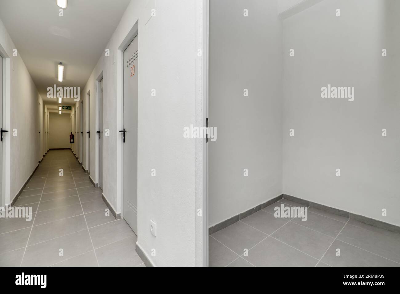 A small empty storage room with white walls and gray tiled floors and a ...