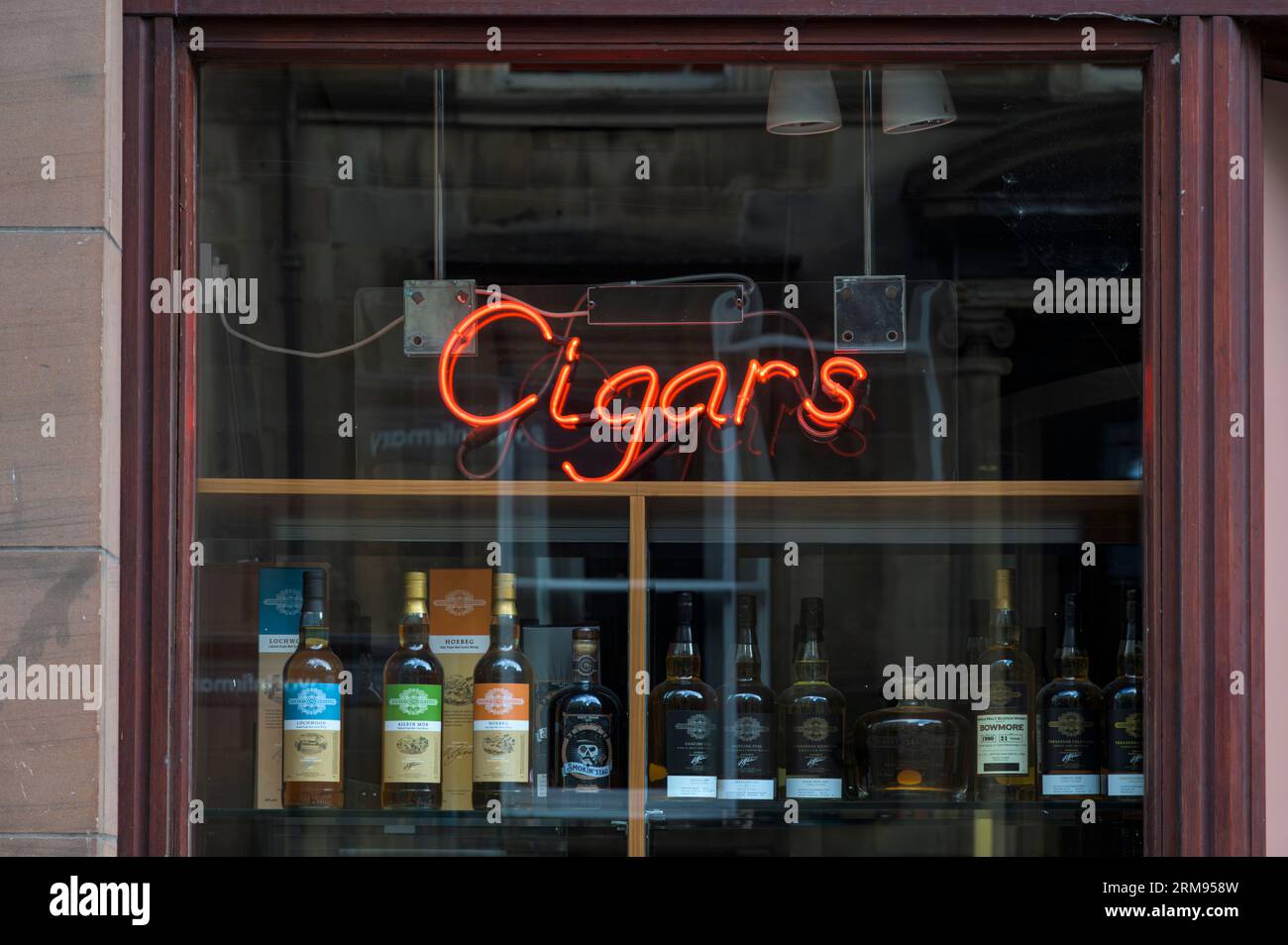 A cigars neon sign and bottles of whisky on display in a shop window ...