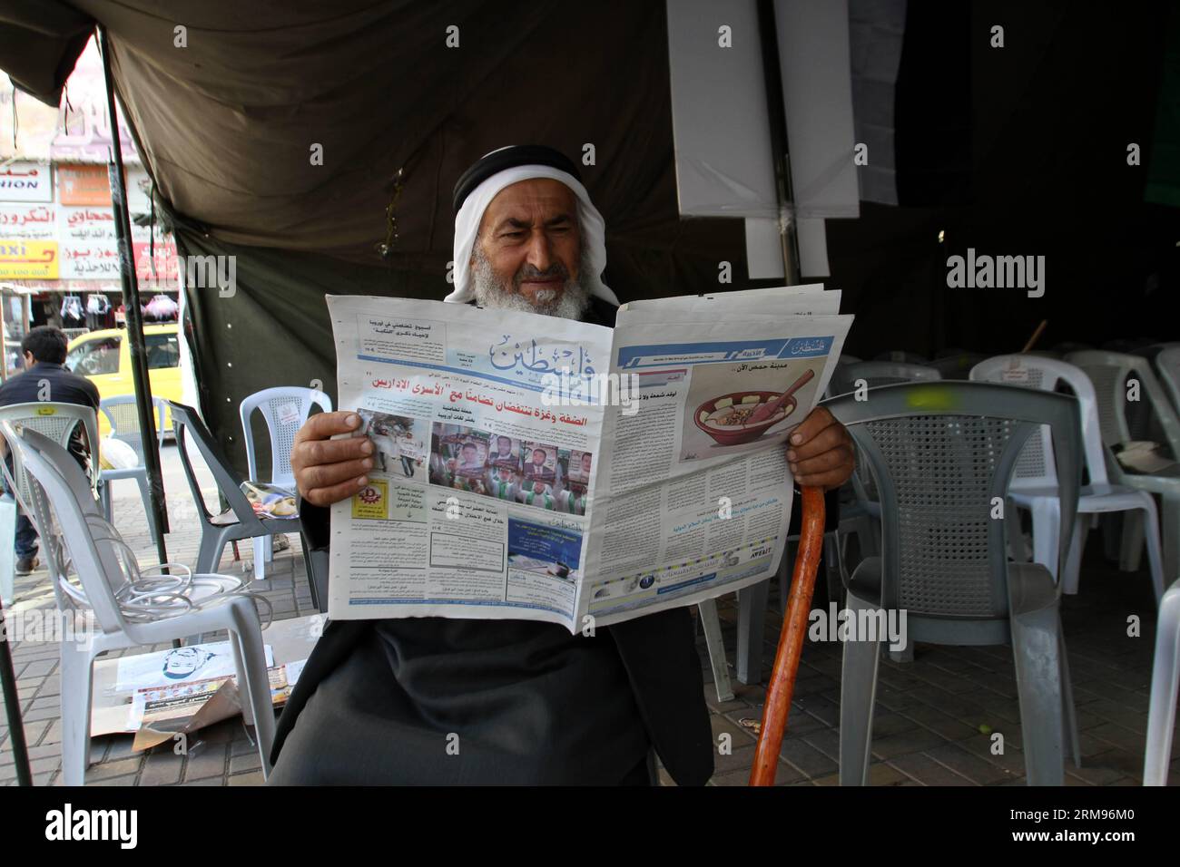 A Palestinian reads a copy of the PALESTINA newspaper in the West Bank ...