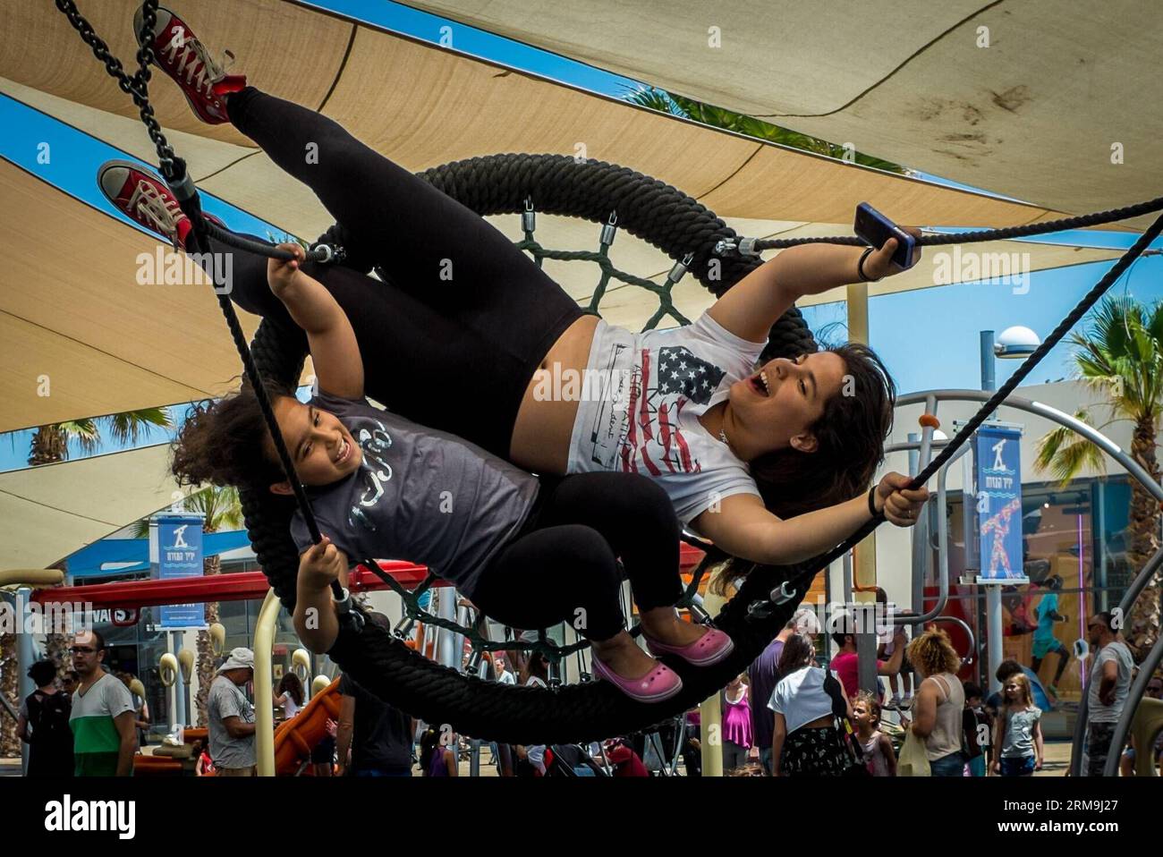 Israeli girls have fun on a swing at a playground in the port of Tel ...