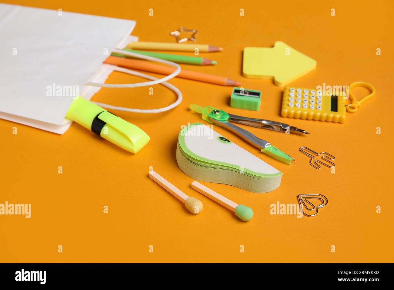Composition with paper bag and different stationery on color background ...