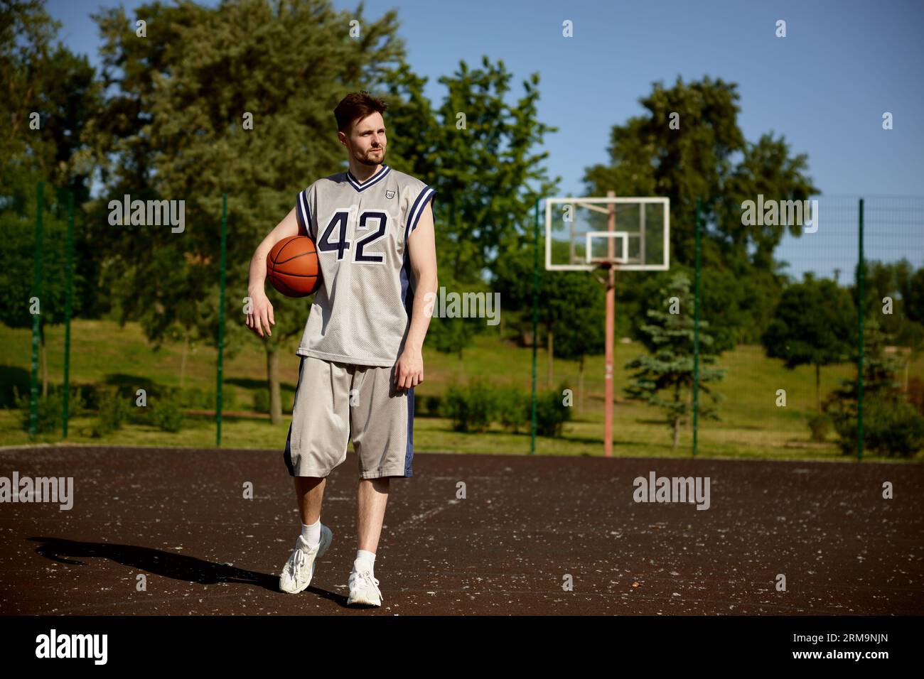 Serious young basketball player on street court full length portrait ...
