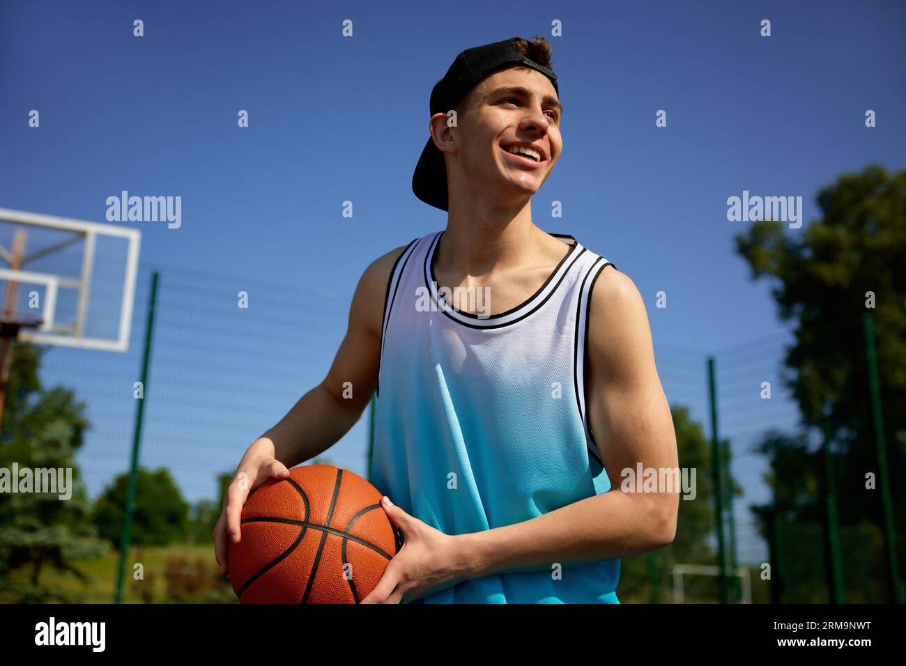 Happy smiling teenager basketball player with ball practicing on ...