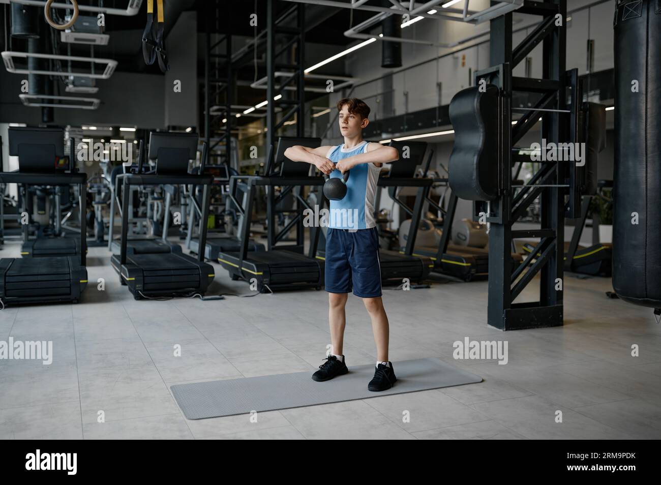 Closeup young sportive boy training with weights lifting kettlebell ...