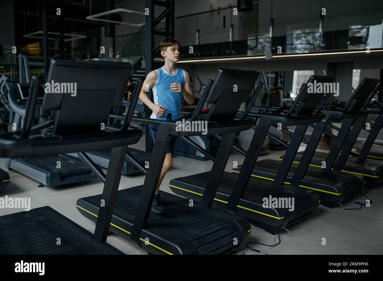 Teenager boy running exercising on treadmill machine at sports gym ...