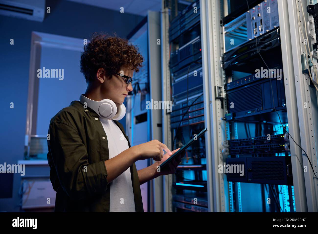 Serious young man working in data center standing at open server rack cabinet Stock Photo - Alamy