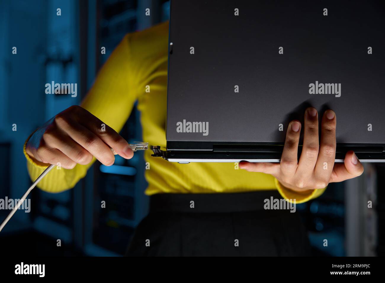 Closeup woman connecting internet network cable to laptop in server ...