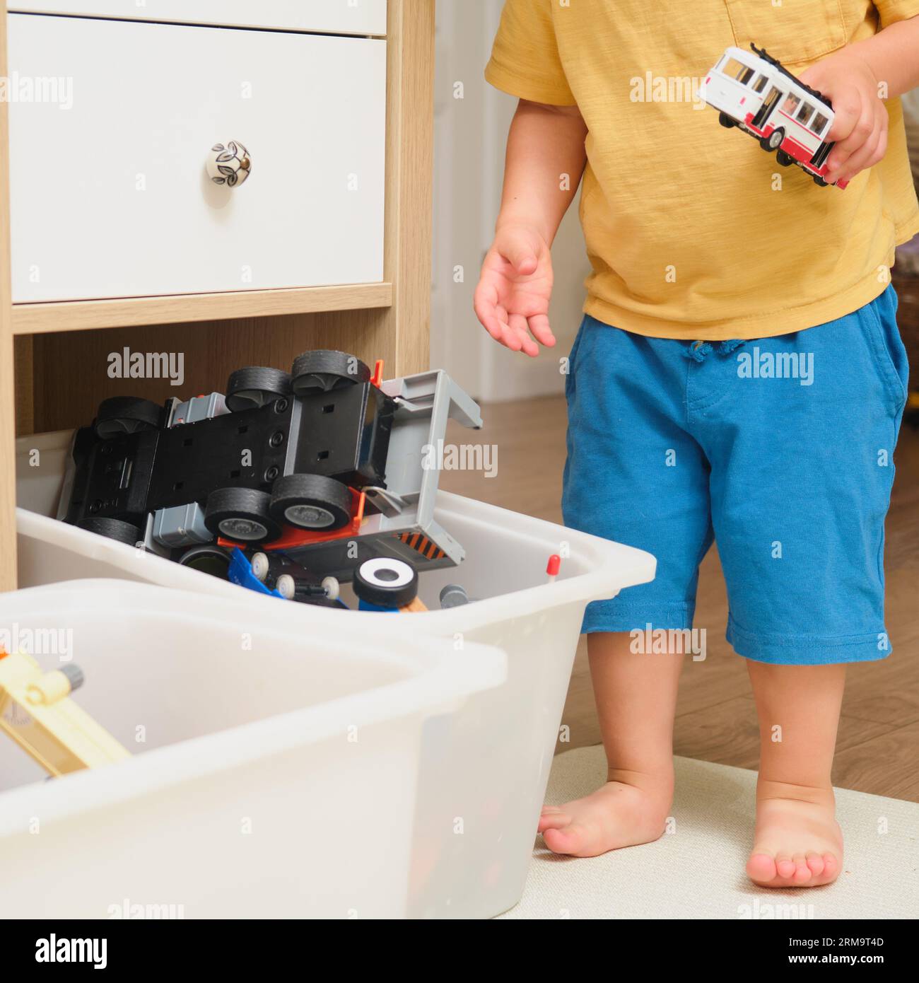 The child is putting the toys back in the box after playing. Kid ...