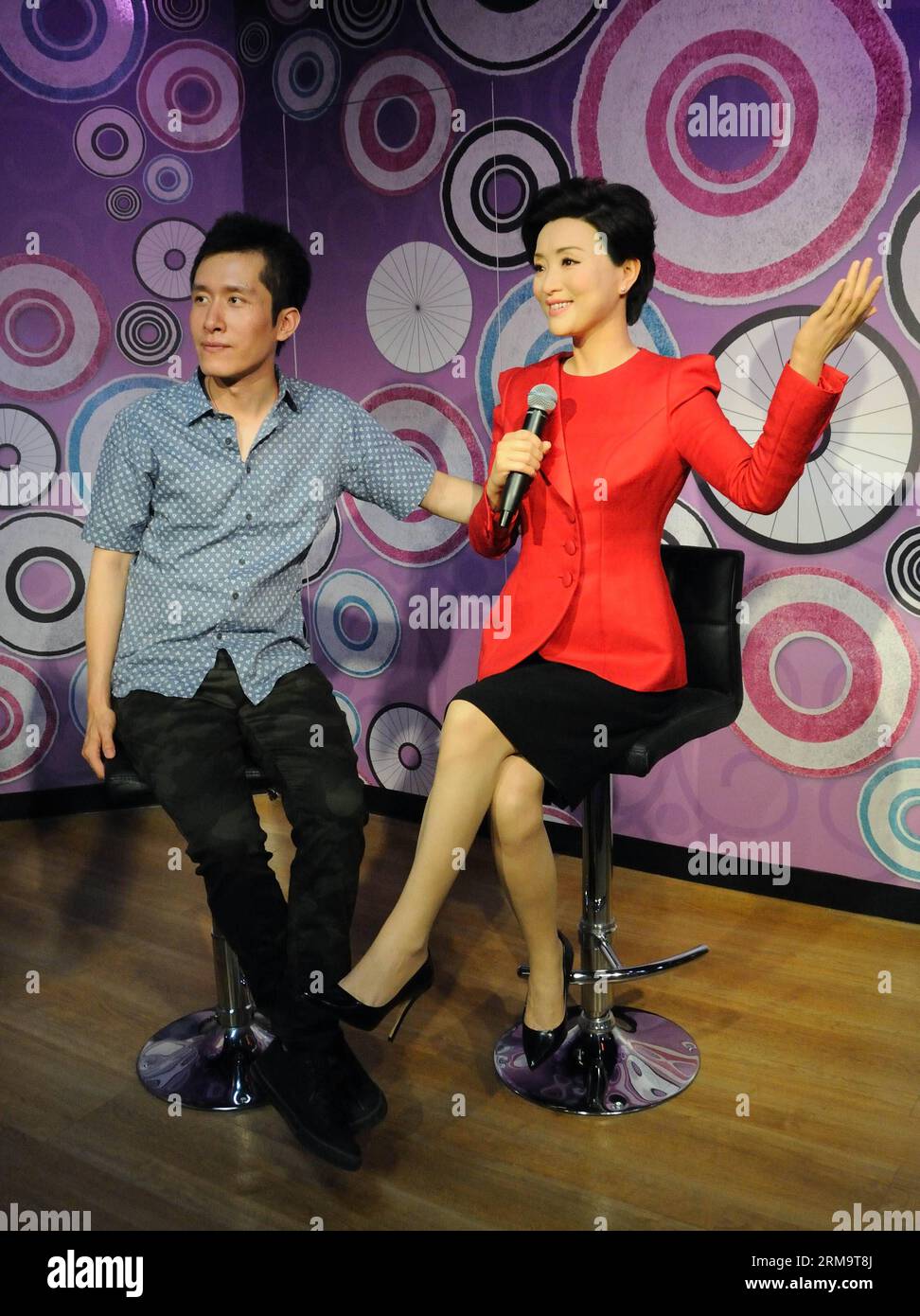 A visitor poses for photos with a wax figure of popular TV hostess Yang ...