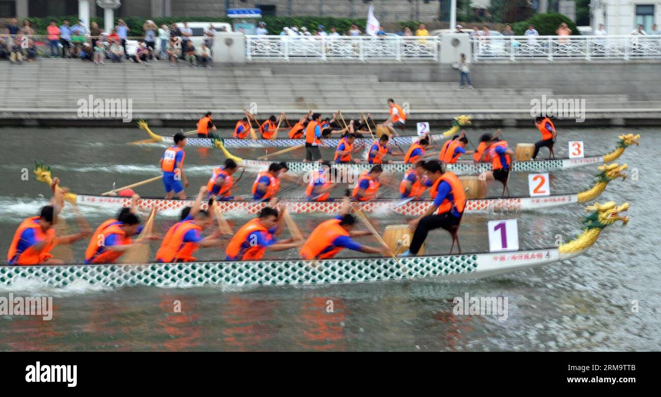 Competitors row dragon boats during a race held on the Haihe River to ...