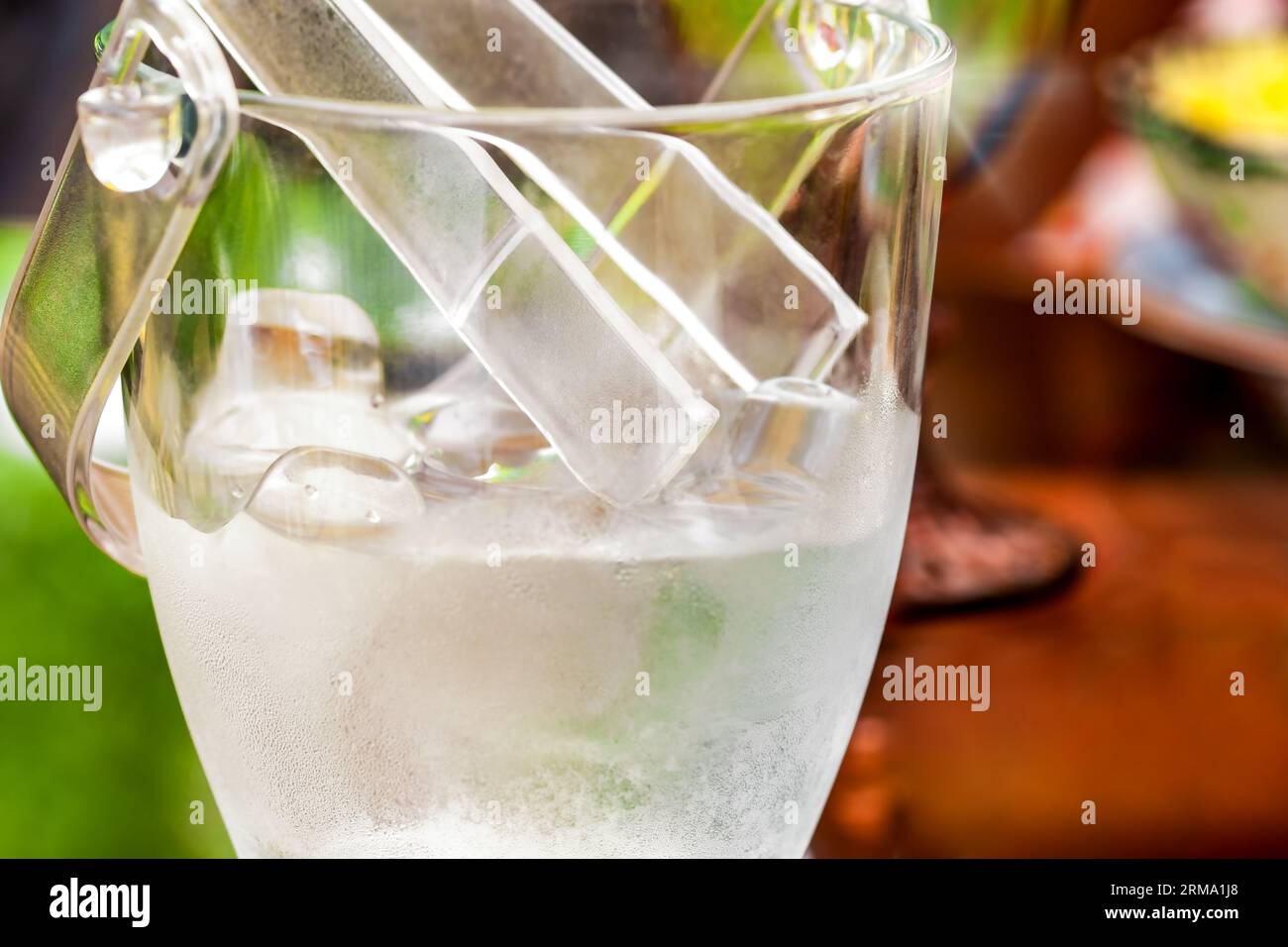 Glass ice bucket at a tropical Caribbean beach. Taking ice cube from ...