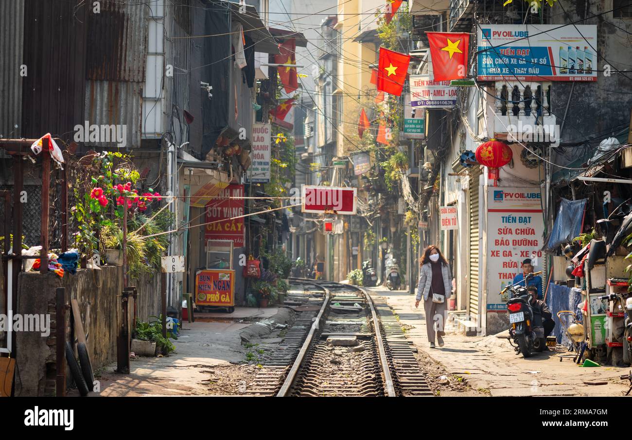 A Vietnamese woman wearing a face mask walks along the main north-south railway line that cuts ...