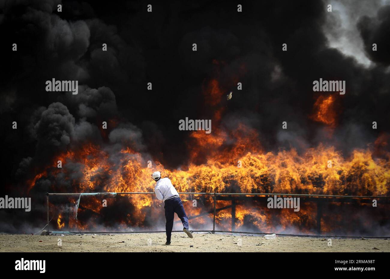 A man throws a pack of illicit drugs into a burning pile of drugs ...