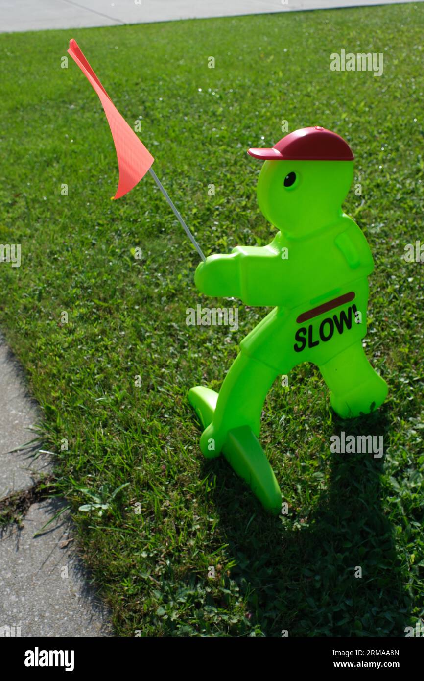 Sign depicting man holding flag to warn drivers to slow for children ...
