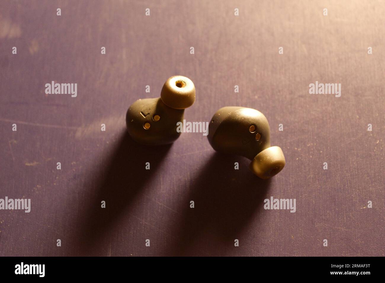 A photo of a two black earbuds in the light on a blue table Stock Photo ...