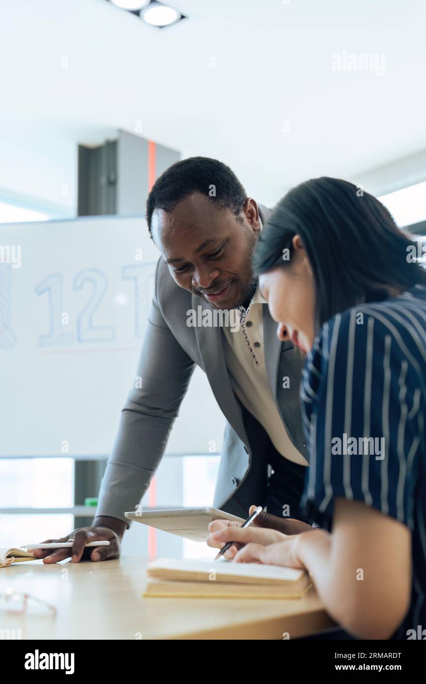 An African American mature professor with classmates in computer lab ...