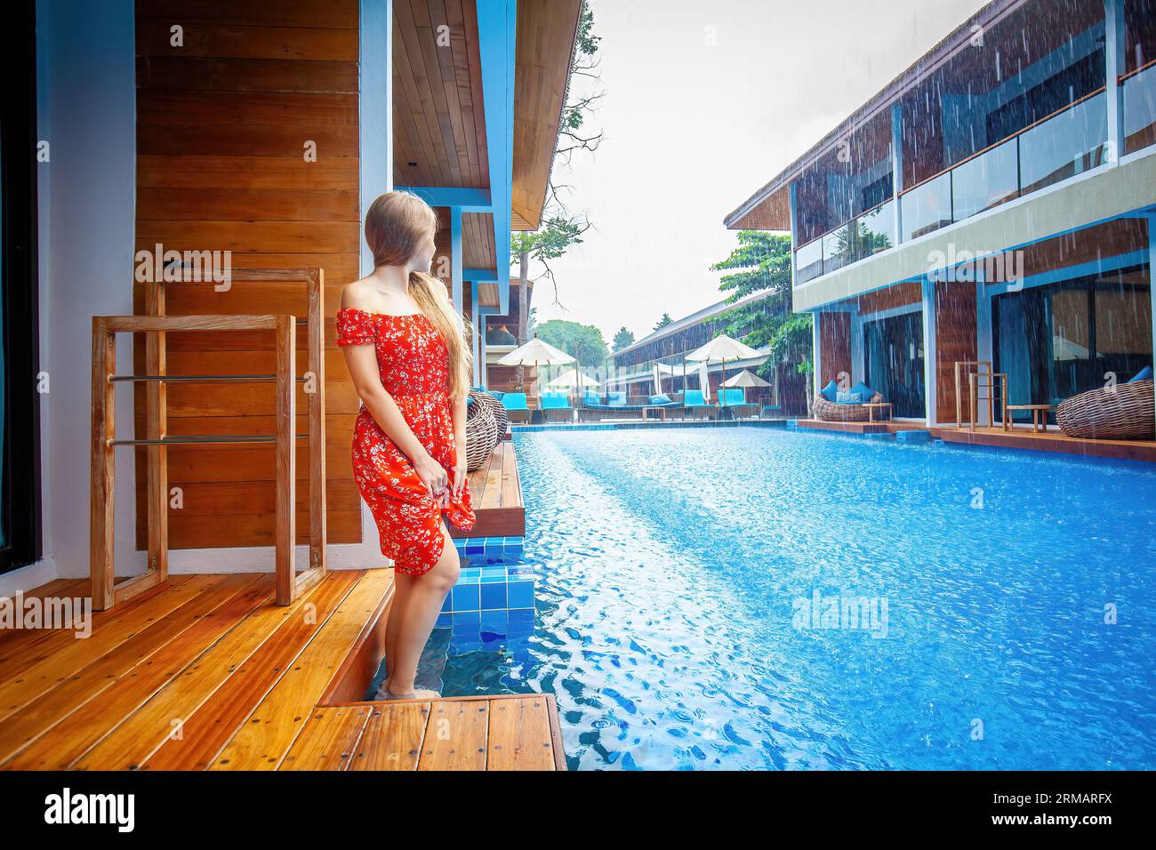 Beautiful woman in red dress enjoys poolside relaxation Stock Photo - Alamy