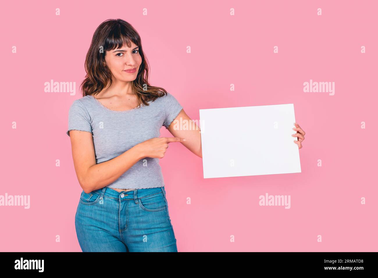Beautiful woman pointing at a blank whiteboard against a pink background Stock Photo - Alamy
