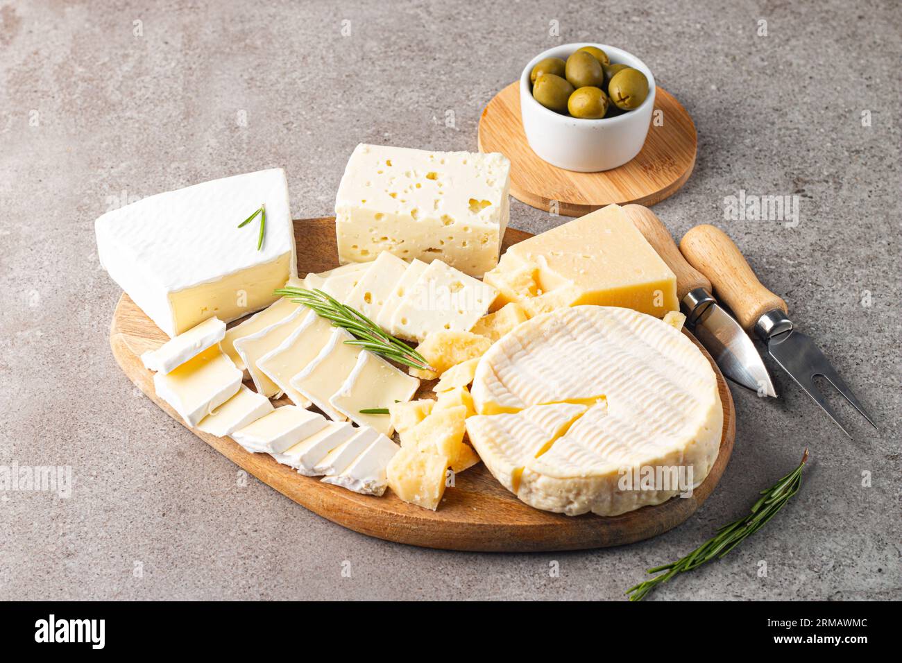 Wooden board with various cheese and olives. Brie. Camembert. Parmesan ...