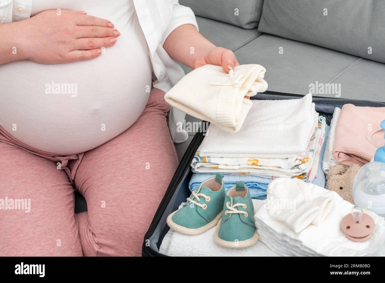 Soon-to-be mom packing her suitcase, anticipating her maternity ...