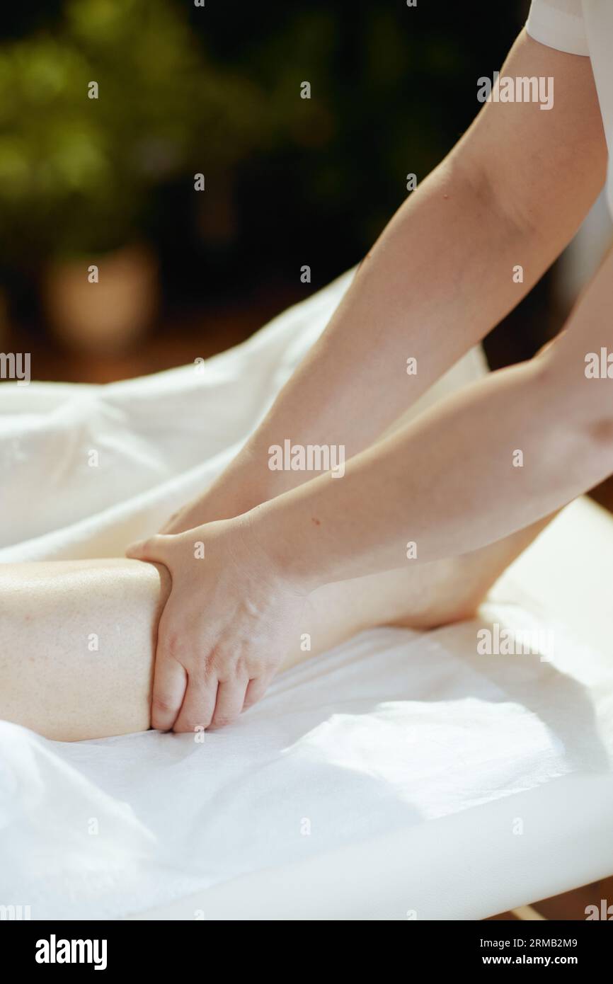 Healthcare time. Closeup on medical massage therapist in massage cabinet massaging clients leg ...
