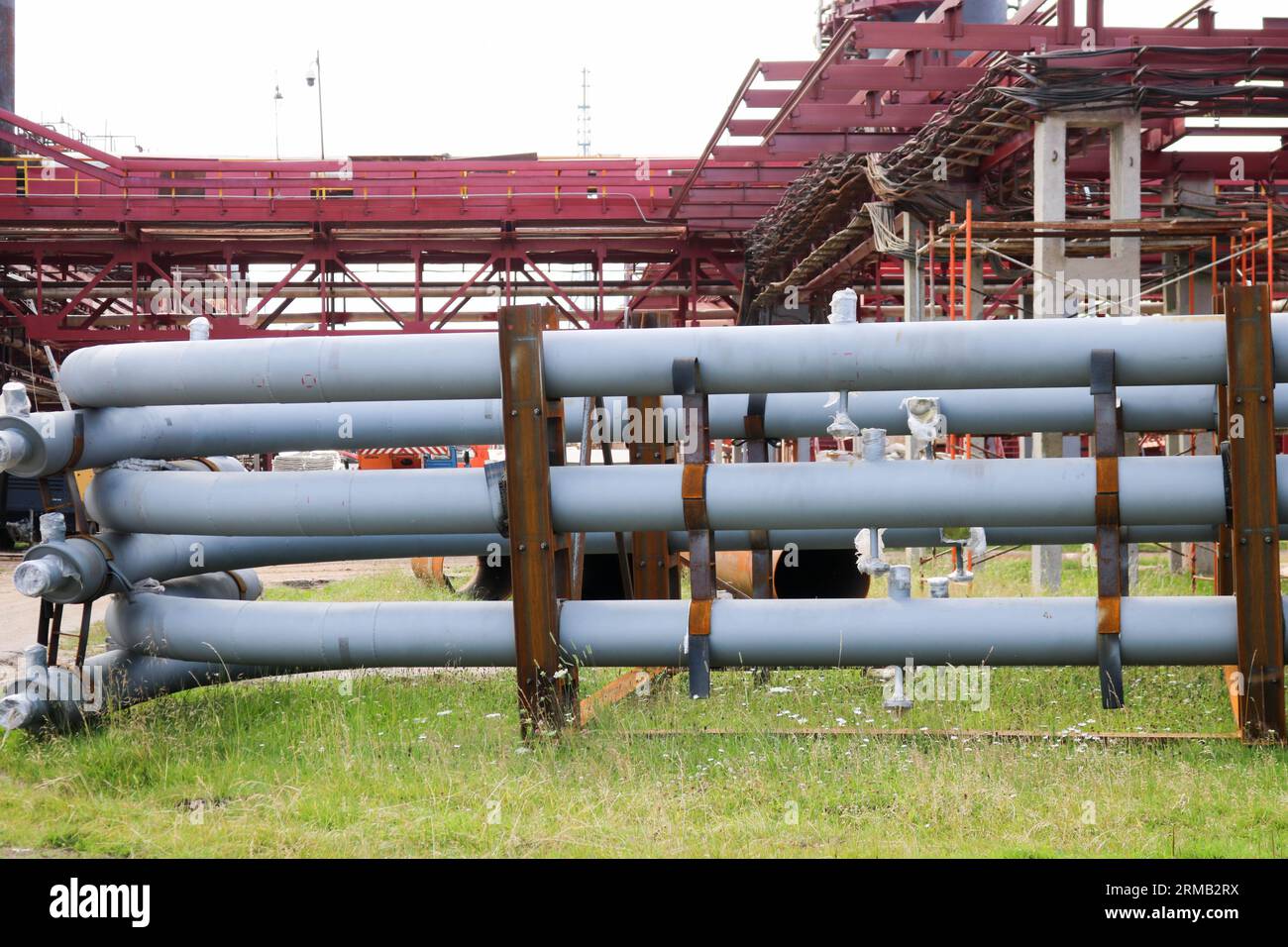 A large iron metal piping trestle with pipes and electric wires and ...