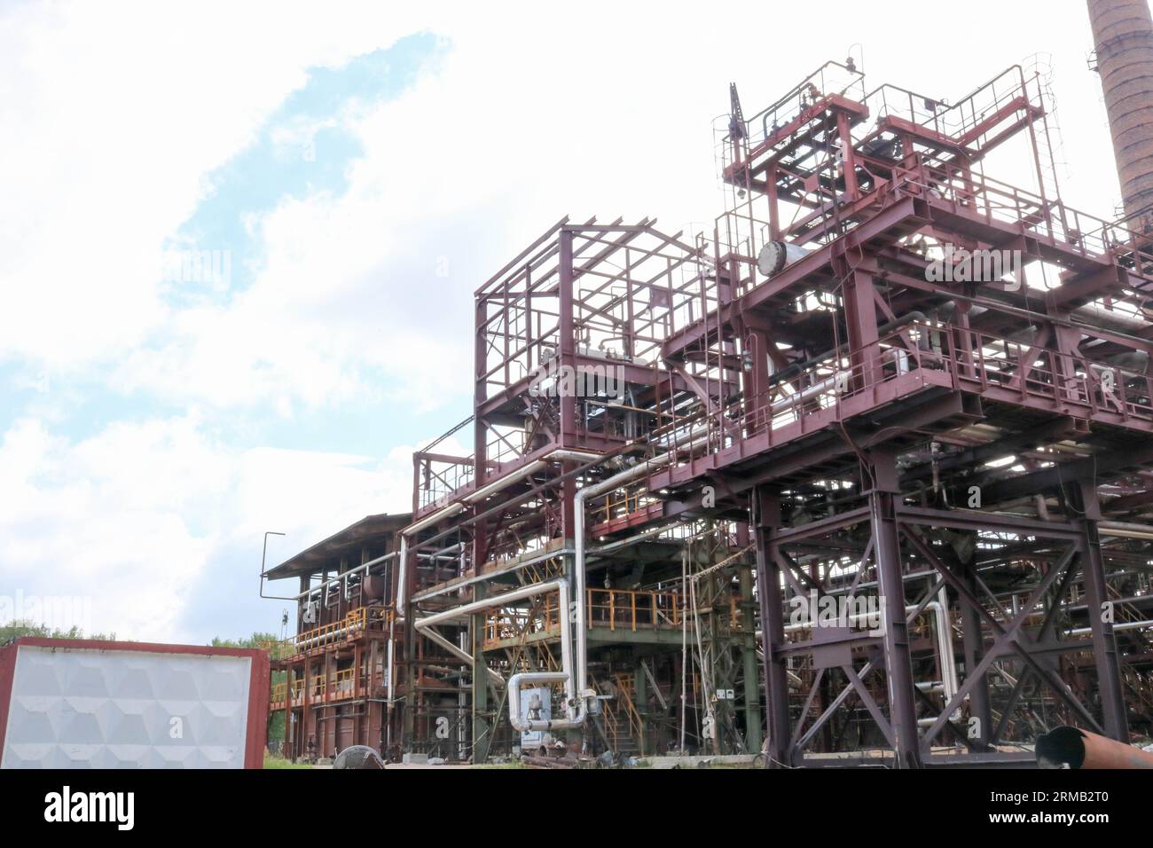 A large iron metal piping trestle with pipes and electric wires and ...